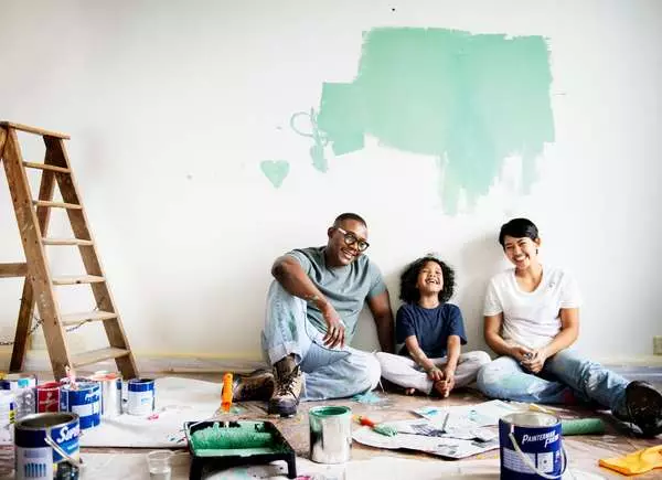 Familie sit in 'n vertrek wat gedeeltelik in groen geverf is