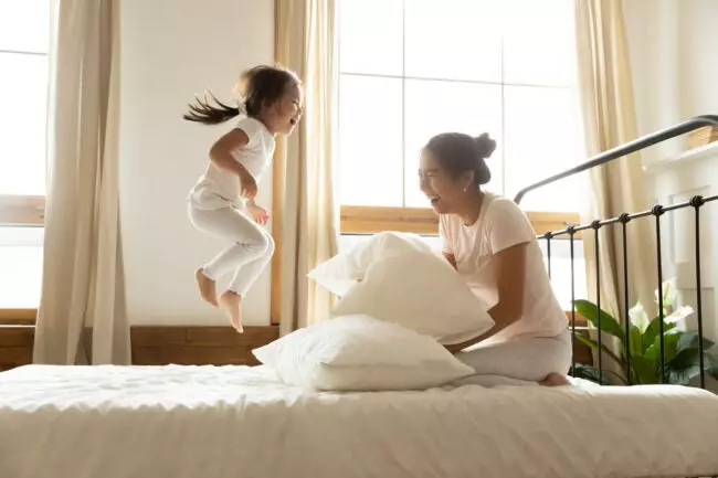 Rano beztroska mała córeczka wskakuje na łóżko, podczas gdy wietnamska matka czuje się szczęśliwa, azjatycka rodzina etniczna w wygodnej piżamie obudź się rozpocznij nowy dzień pozytywny nastrój ciesz się koncepcją aktywnego życia