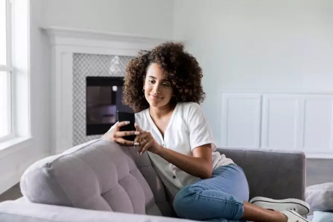 Η γυναίκα χρησιμοποιεί smartphone στο νέο σπίτι