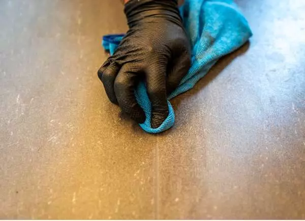 Close-up da mão enluvada azul limpando um chão