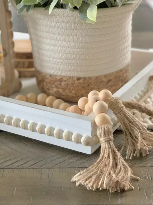 Perlen hängen über einem weißen Tablett mit einer Vase im Hintergrund