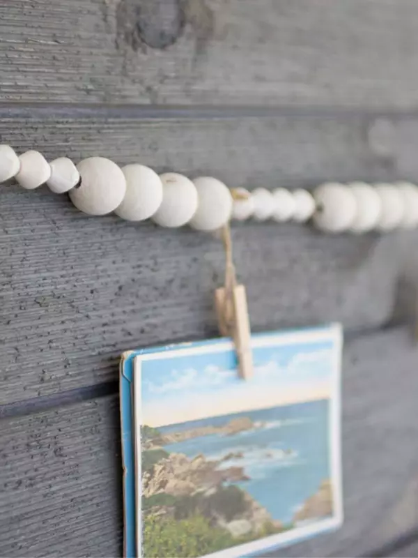 Perlen, die an einer grauen Wand hängen und ein Foto eines Ozeans hochhalten