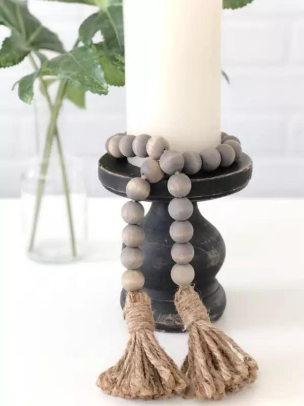 Perlen umwickelt eine weiße Kerze in einem schwarzen Kerzenhalter