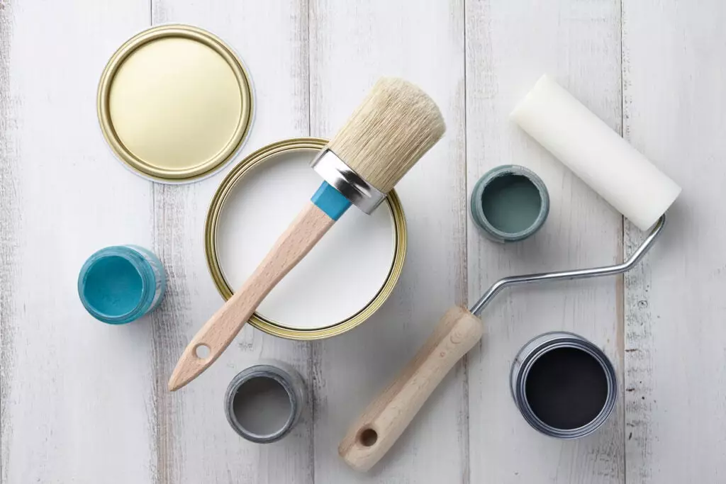 Furçë për bojë, rul sfungjeri, bojëra, dyllë dhe pajisje të tjera për pikturë ose dekorim në dërrasa të bardha druri, pamje nga lart