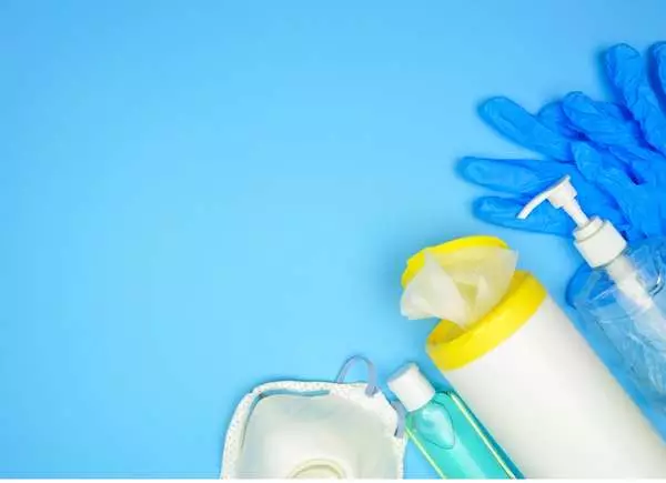 Handschoenen, masker, ontsmettingsmiddel, doekjes in de rechterhoek van een blauwe achtergrond