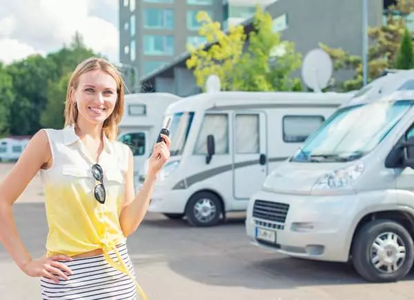 Žena držiaca kľúče stojaca pred radom obytných áut