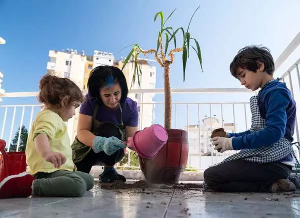 Mare cuidant una planta amb nens en un balcó